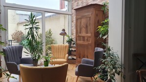 Quarto espaçoso com grandes janelas, um armário de madeira e várias cadeiras.