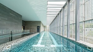 Uma piscina interior moderna com design alongado, guarda-corpos de vidro e chão estampado.