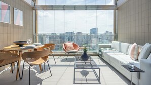 Uma sala de estar moderna com uma janela grande, um sofá, uma mesa de centro e uma área de jantar com cadeiras e uma mesa.