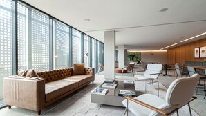 Um interior moderno com um sofá de couro, cadeiras brancas e uma mesa de centro com livros.