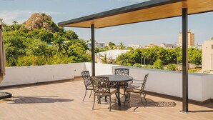 Terraço no telhado com pergolado de madeira, uma mesa redonda e quatro cadeiras.