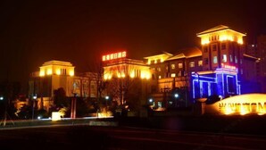 Um hotel com vários edifícios iluminados à noite, com sinalização em destaque e fachada bem iluminada.