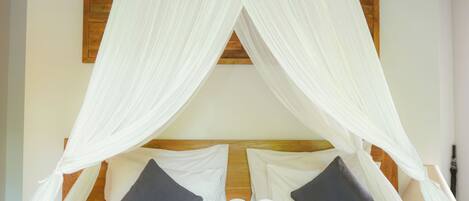 Uma cama com dossel, almofadas e uma mensagem no lençol.