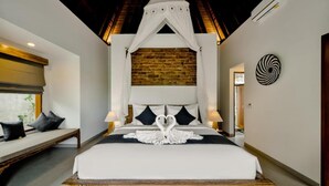 Quarto com uma cama grande, um banco de madeira, uma parede de tijolos e um ventilador de teto.