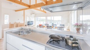 Cozinha moderna com uma ilha grande, eletrodomésticos de aço inoxidável e vista para o exterior.
