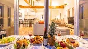 Uma mesa de jantar com comida, bebidas, uma garrafa de vinho e uma abacaxi.