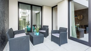 Uma área de estar moderna ao ar livre, com móveis de vime e um vaso de planta.