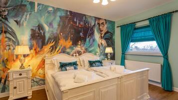 Quarto com um grande mural na parede, uma cama branca, cortinas verde-água e duas luminárias de cabeceira.