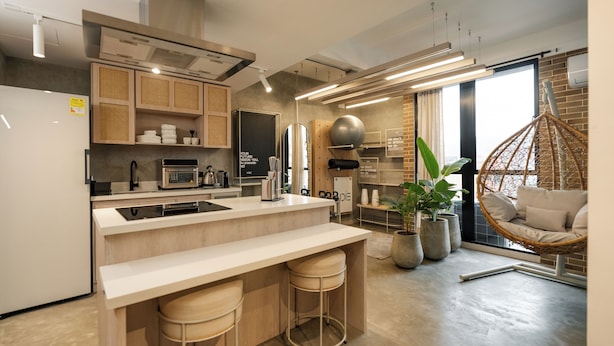 Cozinha moderna com ilha central, banquetas, cadeira suspensa e uma janela grande com vista.