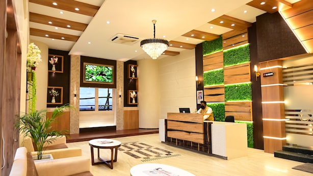 Uma área de recepção moderna com um balcão de madeira, um candelabro e uma parede verde com jardins verticais.