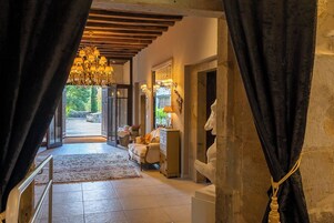 Um corredor espaçoso com lustre, sofá, armário e vista para o exterior.