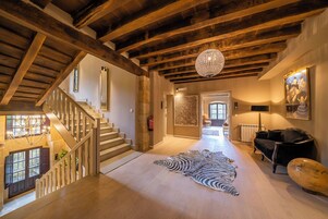 Um interior espaçoso com escada de madeira, um candelabro, um tapete de zebra e um sofá preto.