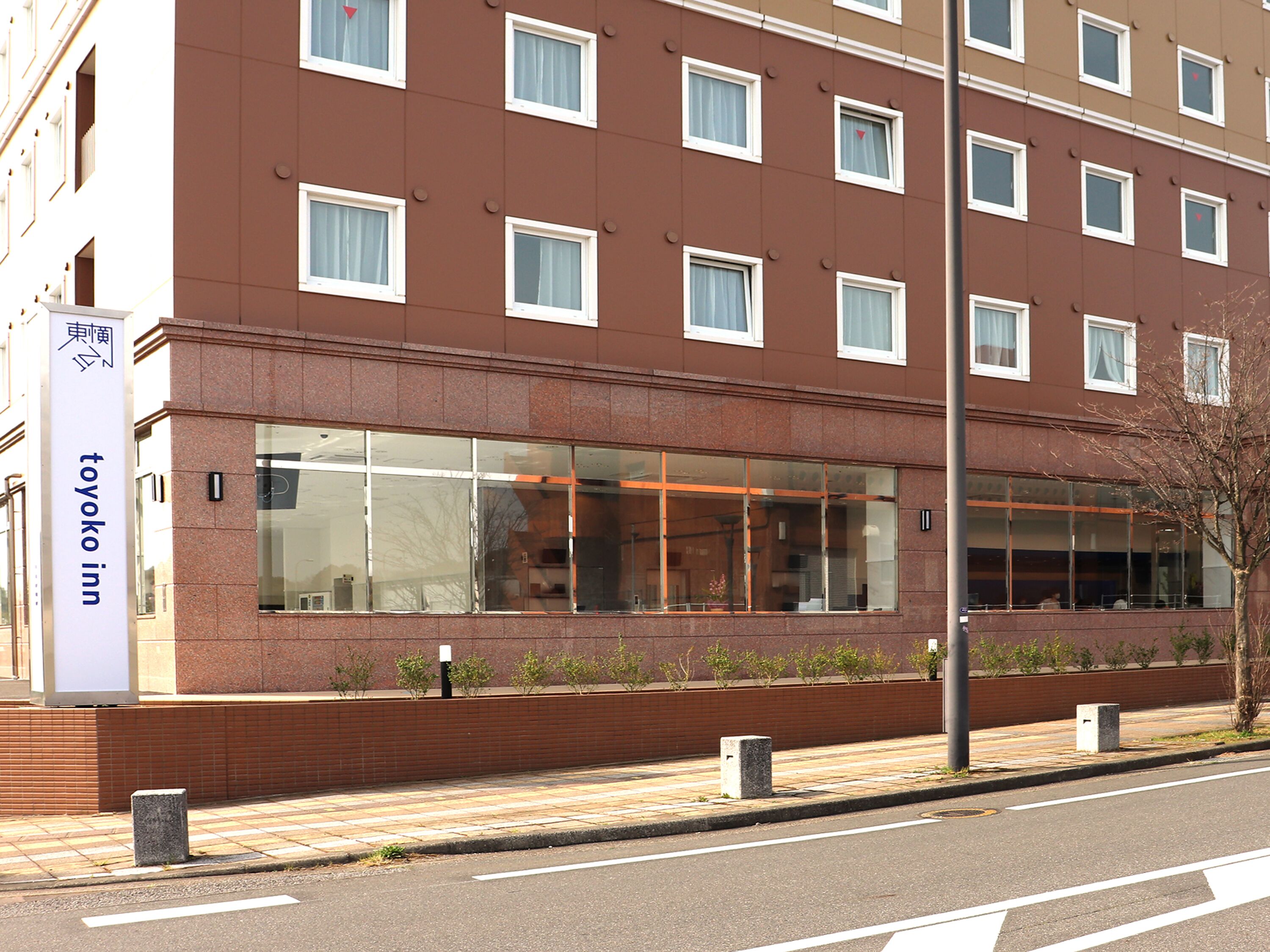 Um hotel moderno com fachada marrom, grandes janelas e uma placa indicando "Toyoko Inn".