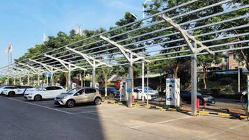 Área de estacionamento coberta com vários carros, um quiosque e uma bandeira.