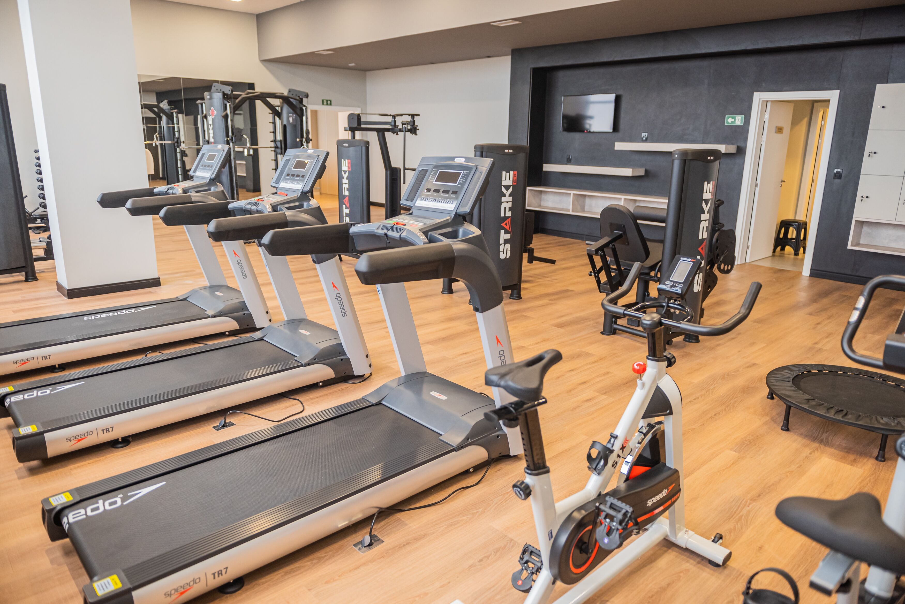 Academia com várias esteiras, bicicletas ergométricas e aparelhos de musculação.