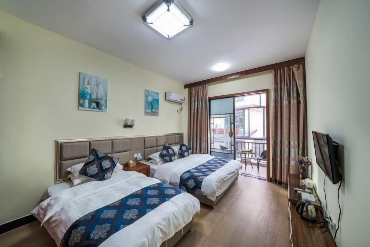 Quarto de hotel com duas camas, televisão de tela plana, varanda e vista para o exterior.