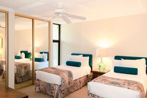 Quarto de hotel com duas camas, um ventilador de teto e um espelho.