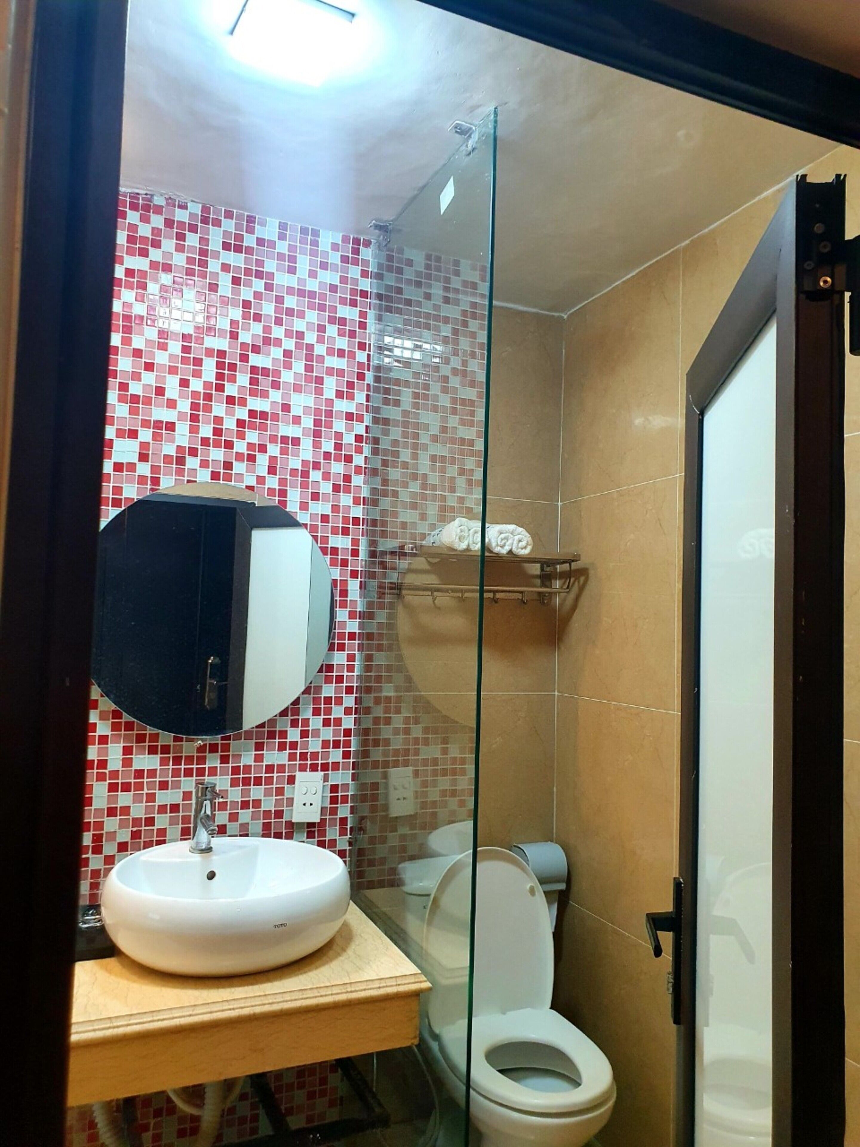 Casa de banho com lavatório branco, espelho, sanita e zona de duche.