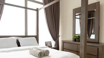 Quarto de hotel com uma cama grande, uma mesinha de cabeceira de madeira, um espelho e uma janela com cortinas.