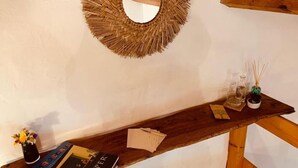 Uma prateleira de madeira rústica com um espelho, um pequeno vaso com flores e alguns livros.