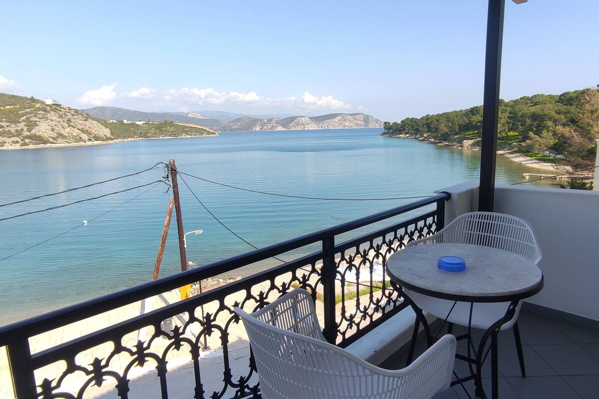 Varanda com vista para um mar tranquilo e colinas ao longe.