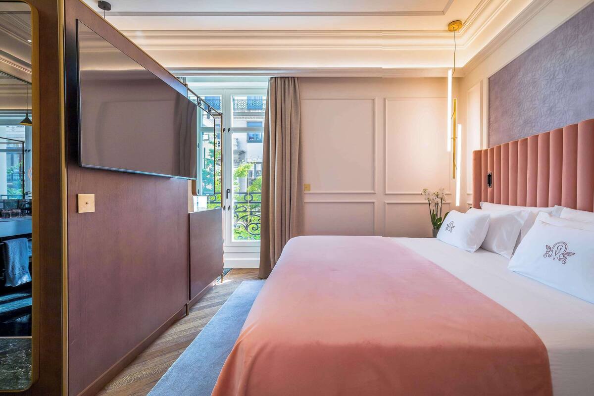 Quarto de hotel com cama, escrivaninha e vista para o exterior.