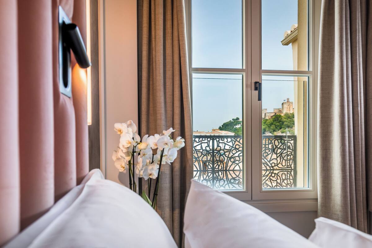 Quarto de hotel com vista para uma varanda e o horizonte da cidade.