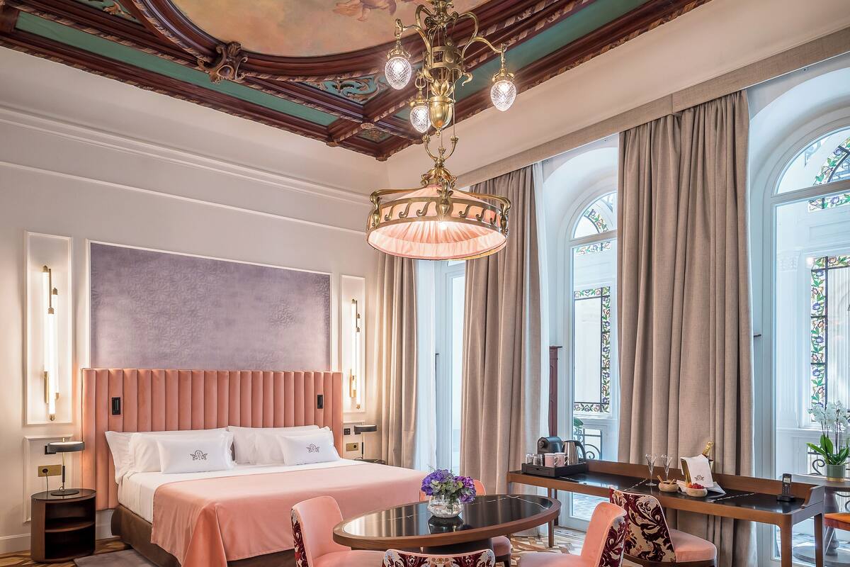 Quarto de hotel luxuoso com uma cama grande, uma mesa de jantar e um candelabro.