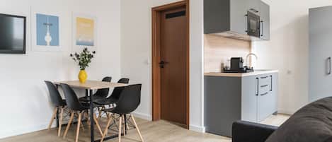 Um apartamento moderno com sala de jantar, cozinha compacta e área de estar.