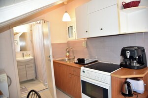 Uma cozinha compacta com fogão, pia e cafeteira.