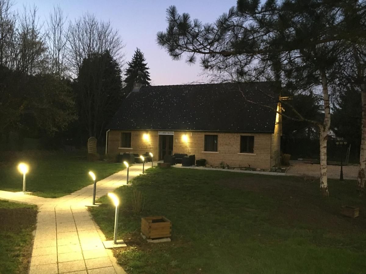 Um edifício de dois andares com telhado inclinado, entrada bem iluminada e acesso por calçada.