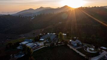 Uma aldeia rural com casas tradicionais, uma estrada sinuosa e uma paisagem acidentada.