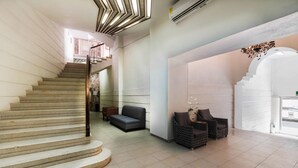 Um interior moderno com escada, área de estar com sofás e teto decorativo.
