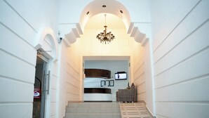 Escadaria que leva a uma sala de estar com televisão, um candelabro e um banco de madeira.
