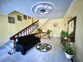 Uma escadaria com guarda-corpos de madeira, um banco preto e plantas em vasos.