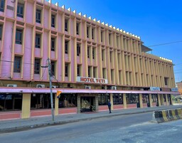 Um edifício rosa com uma placa que diz 'HOTEL YETI'.