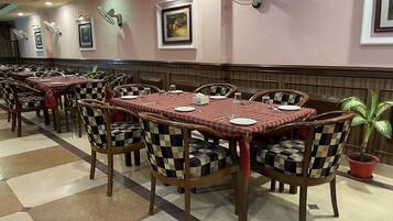 Um restaurante com toalhas de mesa quadriculadas, cadeiras de madeira e obras de arte emolduradas nas paredes.