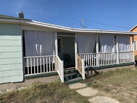 Uma casa térrea com varanda, chaminé e o número 208 na parede.