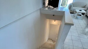 Uma escada leva a um patamar onde há um monitor de computador sobre uma mesa.