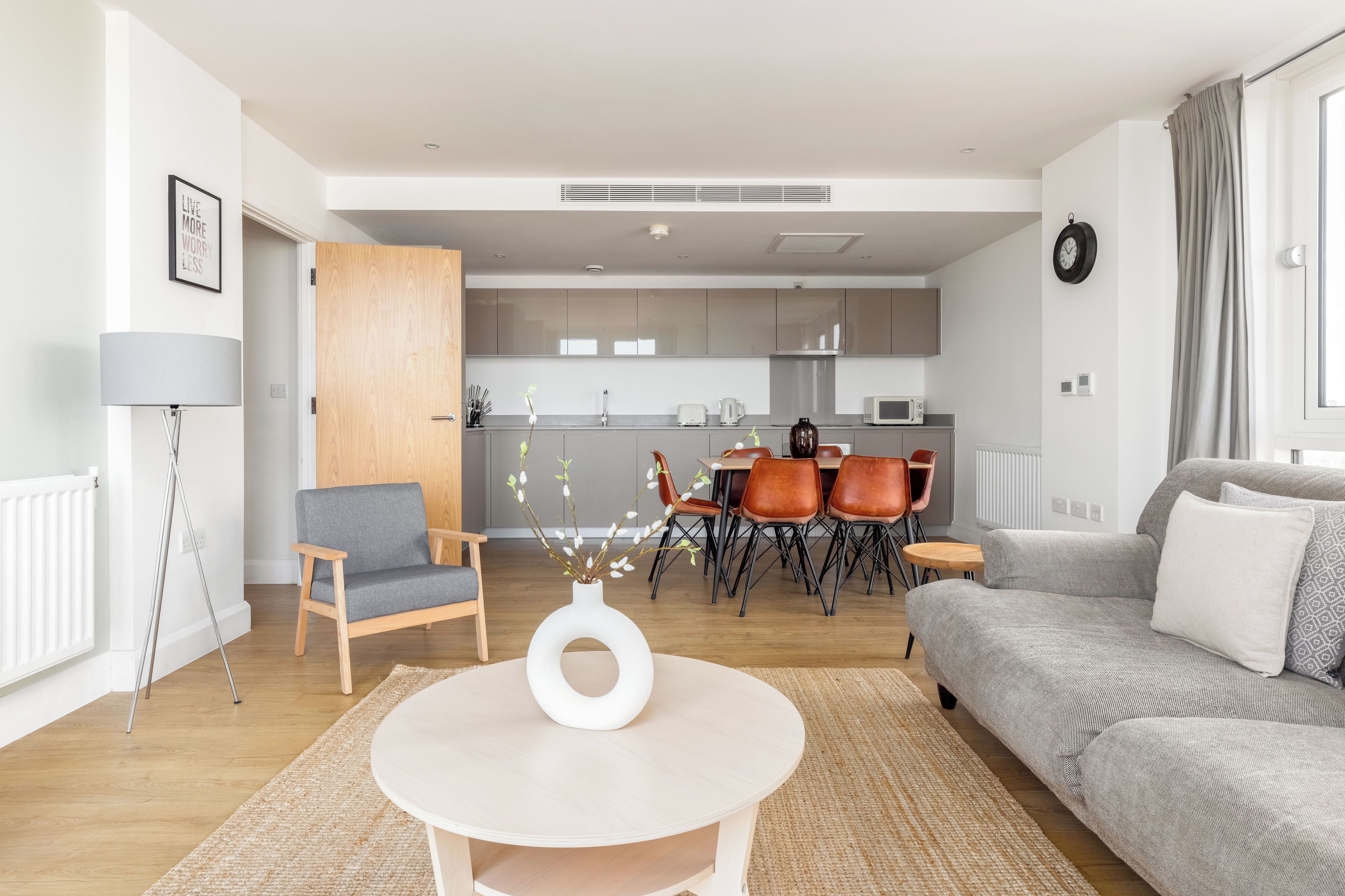 Uma sala de estar moderna com um sofá, uma mesa de centro e uma área de jantar ao fundo.