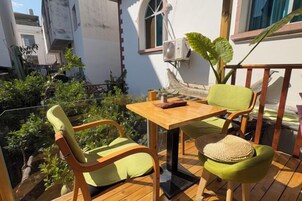 Um deck de madeira com mesa e cadeiras, cercado por vegetação.