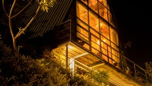 Um edifício com uma grande estrutura em forma de cúpula iluminada no topo, rodeado por vegetação densa.