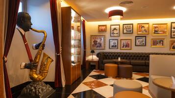 Quarto com uma grande estátua de um homem tocando saxofone, um sofá, uma mesa de centro e quadros nas paredes.
