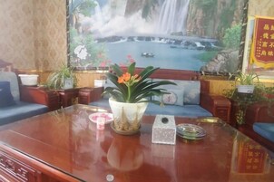Quarto com uma grande pintura de uma cachoeira, um sofá, uma mesa com planta em vaso e uma placa decorativa.