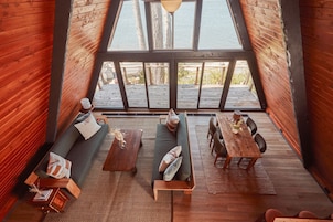 Interior acolhedor de madeira com uma grande janela com vista para um alpendre.