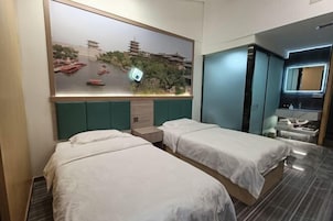 Quarto de hotel com duas camas, uma televisão grande fixada na parede, banheiro moderno com espelho e vista para arquitetura tradicional.