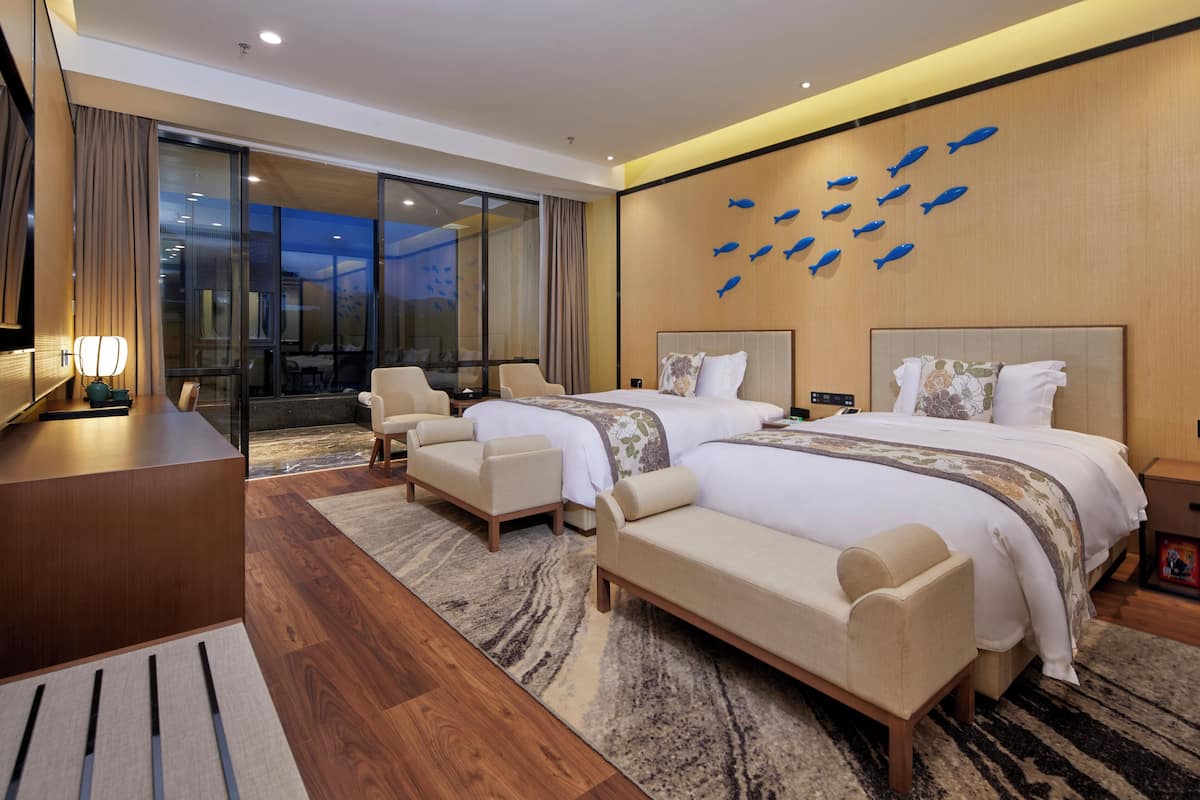 Quarto de hotel moderno com duas camas, uma mesa e um espaço de estar.