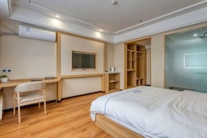Um quarto com uma cama, uma escrivaninha, uma cadeira e um guarda-roupa.