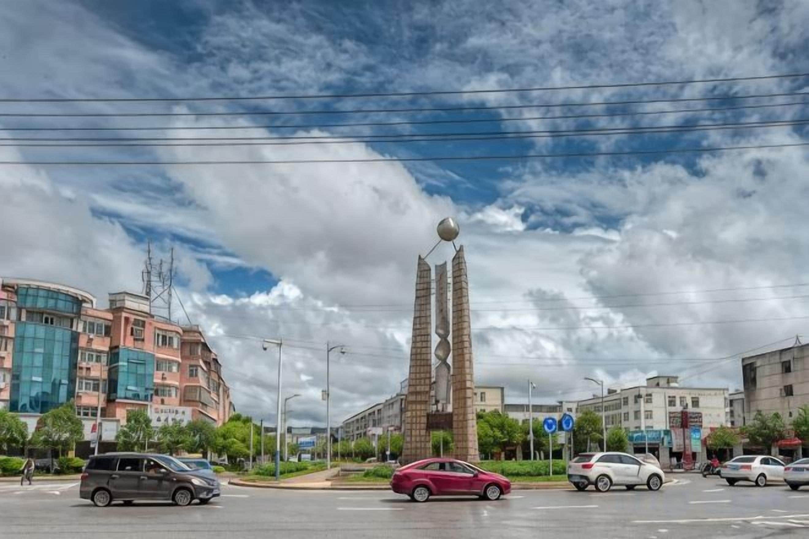 Cruzamento urbano com um monumento alto, edifícios e carros.