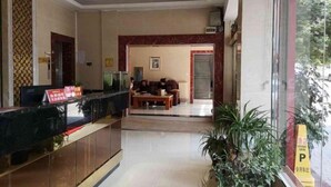 Área de recepção de hotel com balcão, espaço de estar e vista para o exterior.